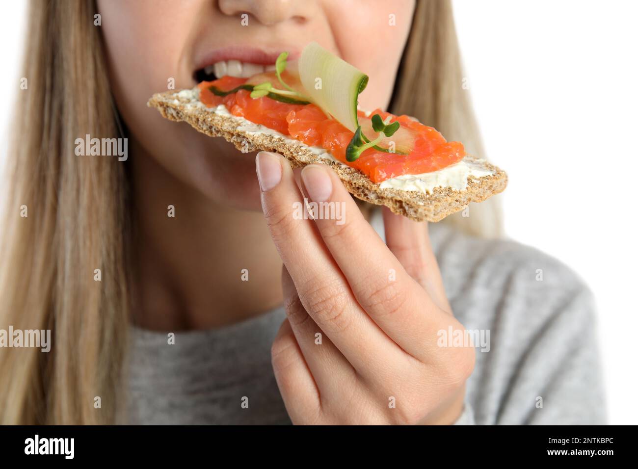 Woman eating fresh rye crispbread with cream cheese, salmon and ...