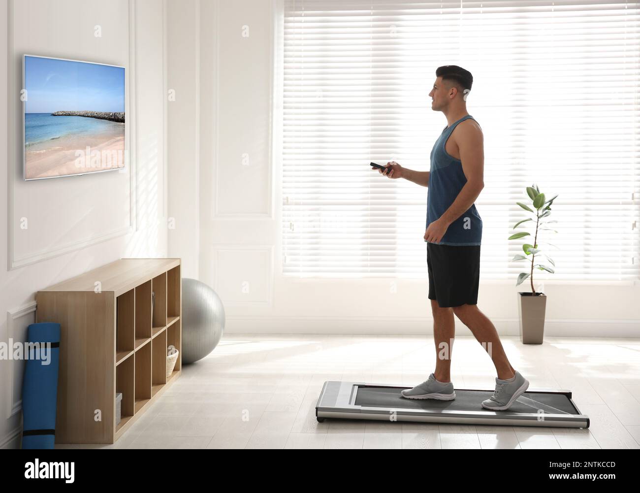 Sporty man with remote control training on walking treadmill and ...