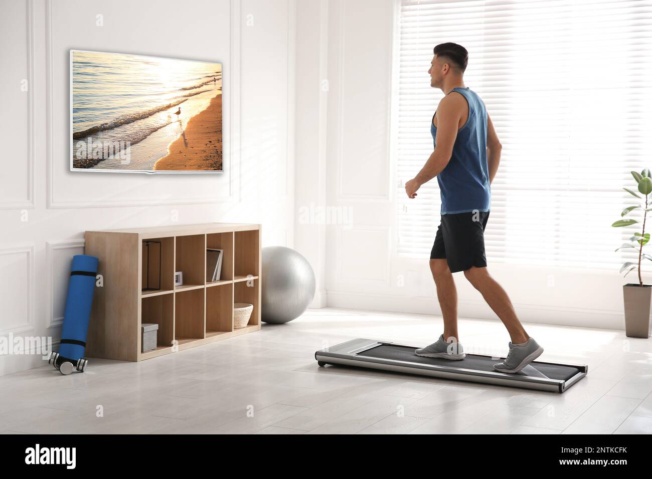 Sporty man training on walking treadmill and watching TV at home Stock ...