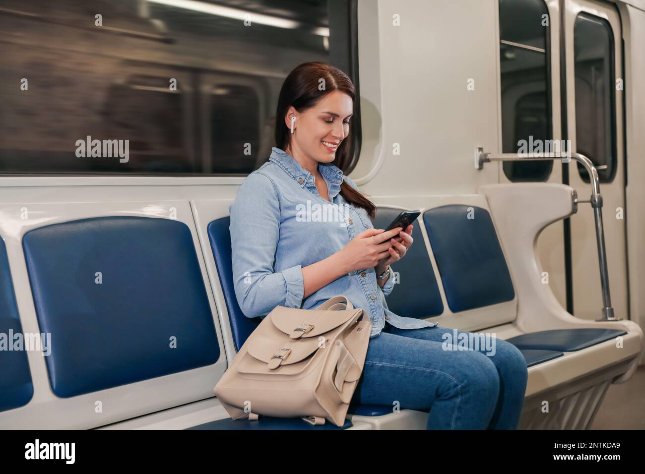 Beautiful woman with mobile phone and earbuds listening to music in ...