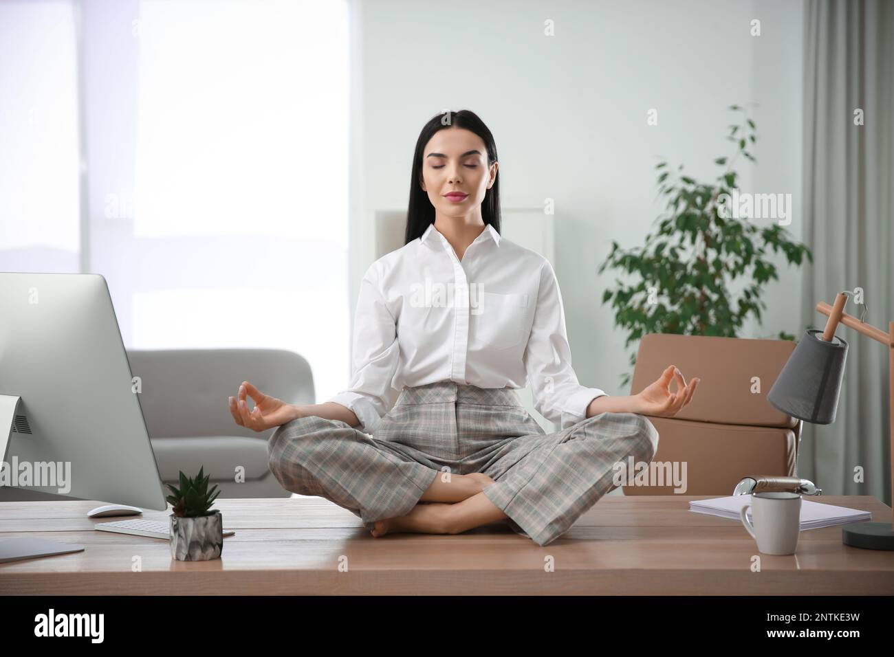 Young woman meditating at workplace. Stress relief exercise Stock Photo ...