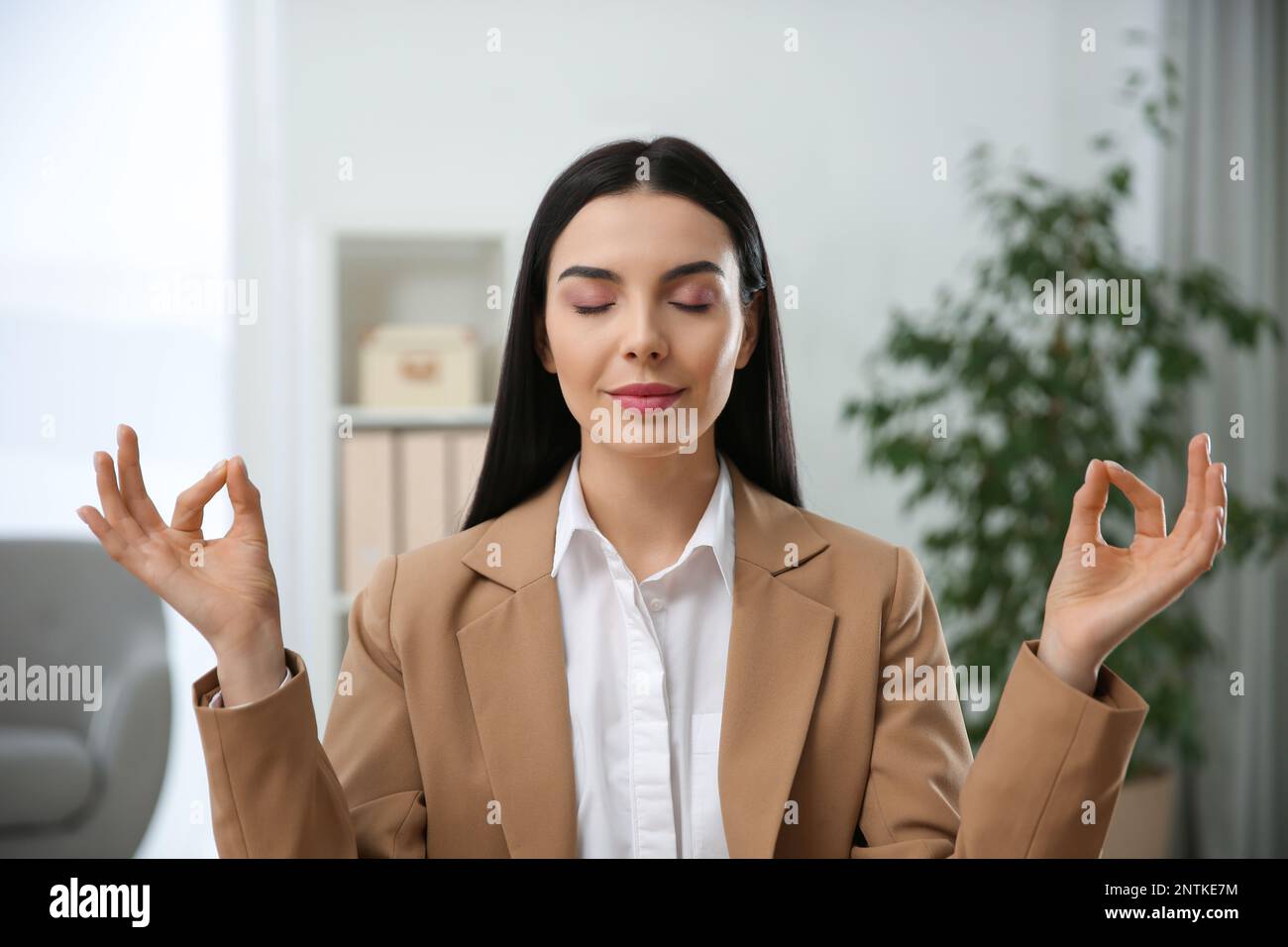 Young woman meditating at workplace. Stress relief exercise Stock Photo ...