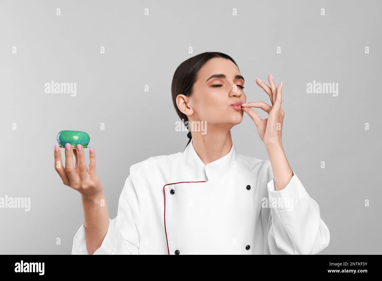 Professional confectioner in uniform with cake showing delicious ...