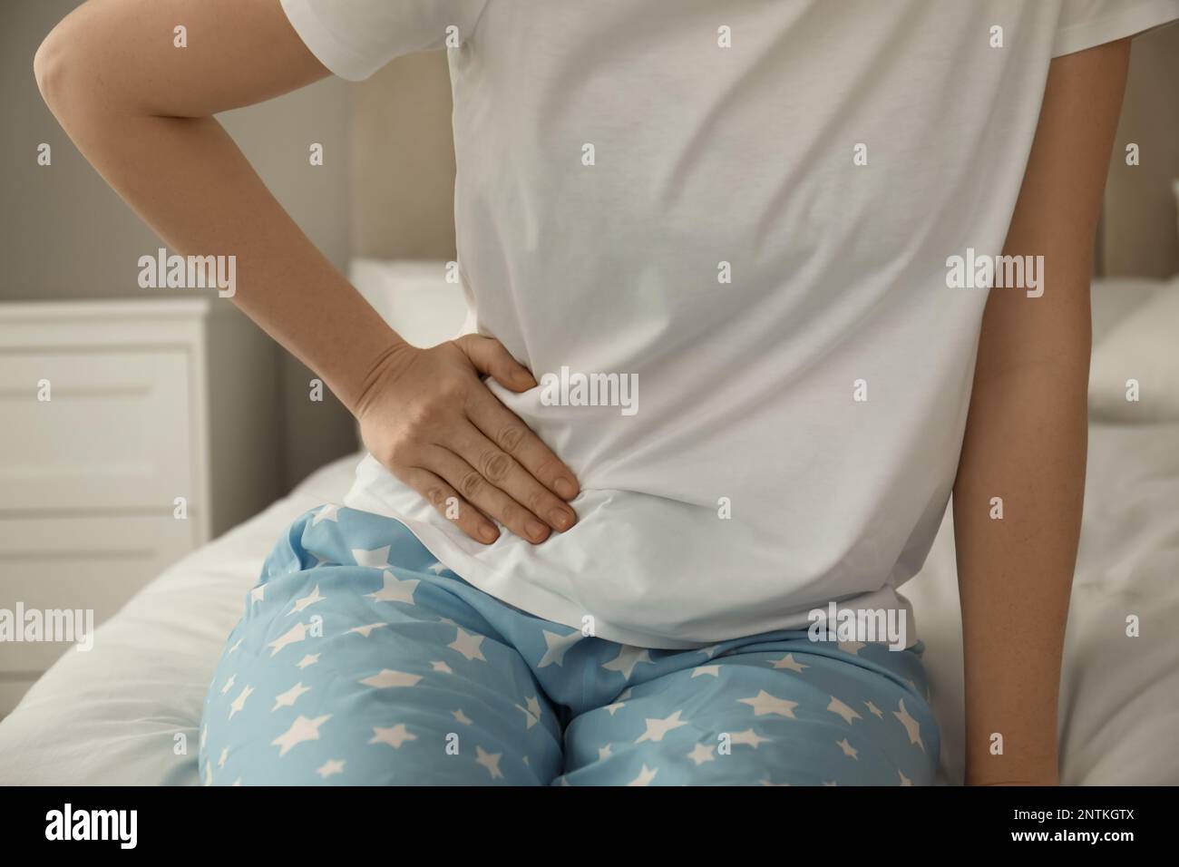 Woman suffering from appendicitis inflammation on bed at home, closeup ...