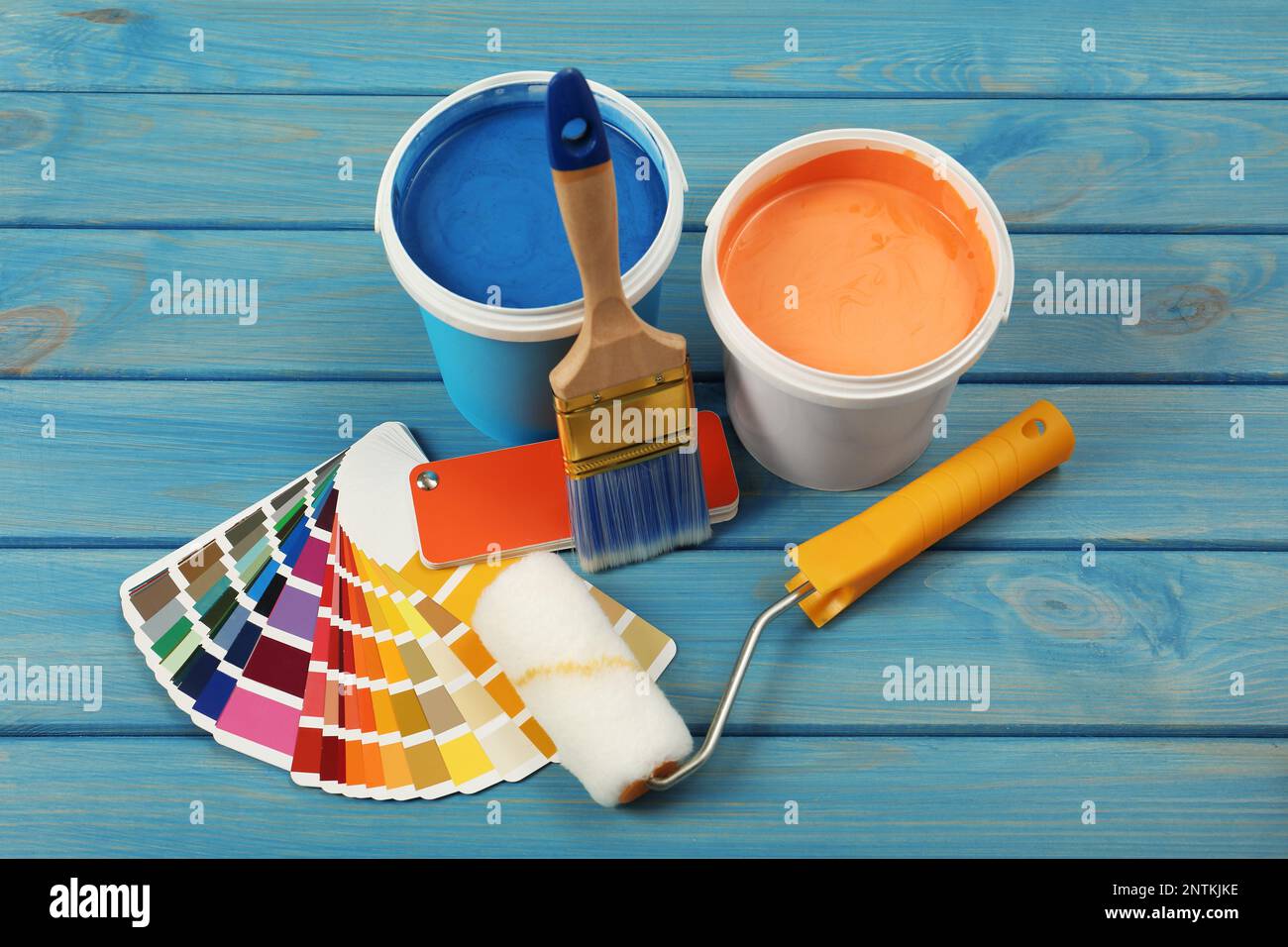 Buckets of paints, palette and decorator's tools on blue wooden ...