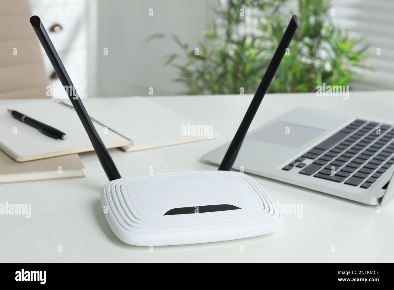 Modern wi-fi router and laptop on white table indoors Stock Photo - Alamy