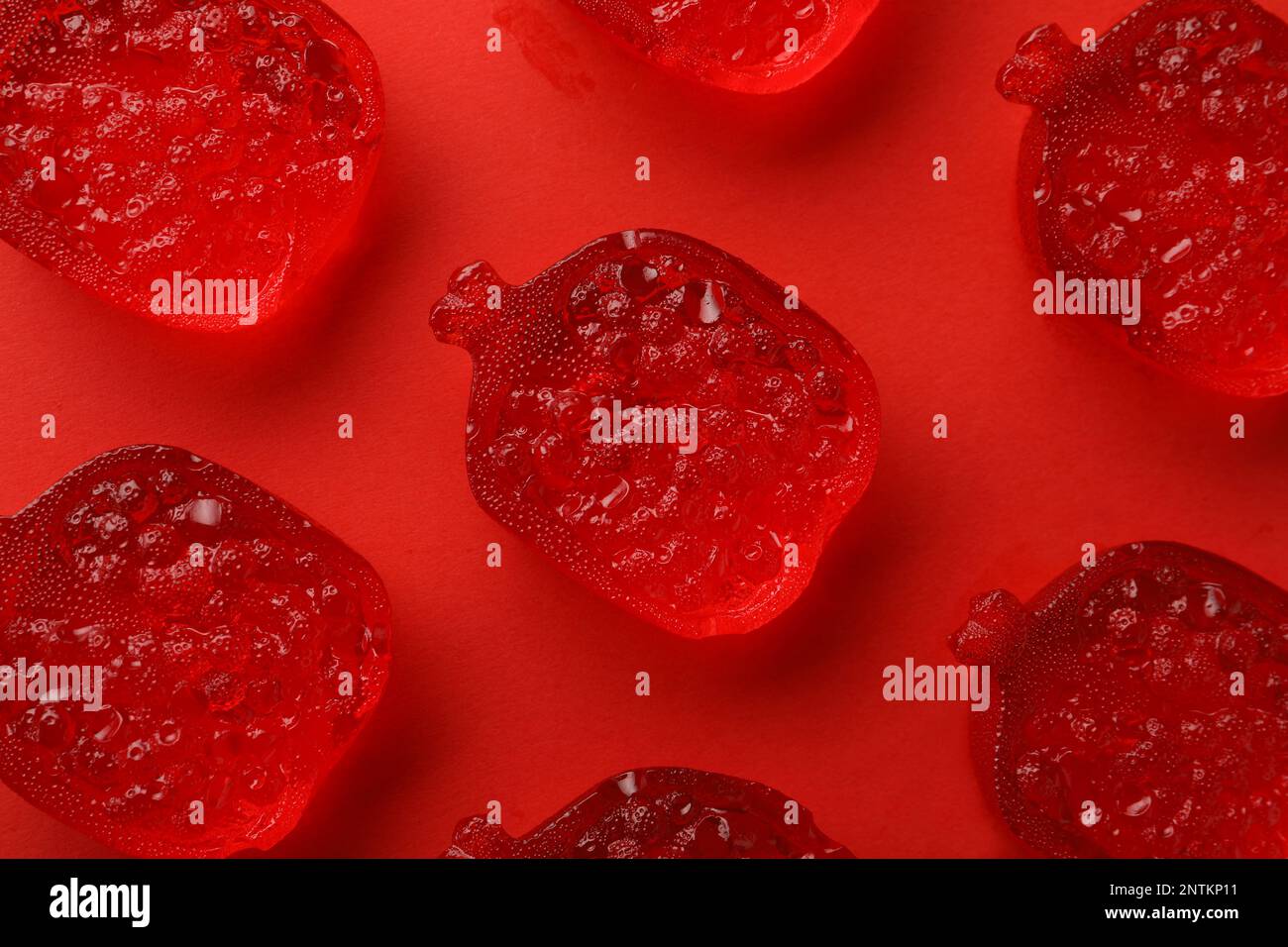 Delicious gummy pomegranate candies on red background, flat lay Stock ...