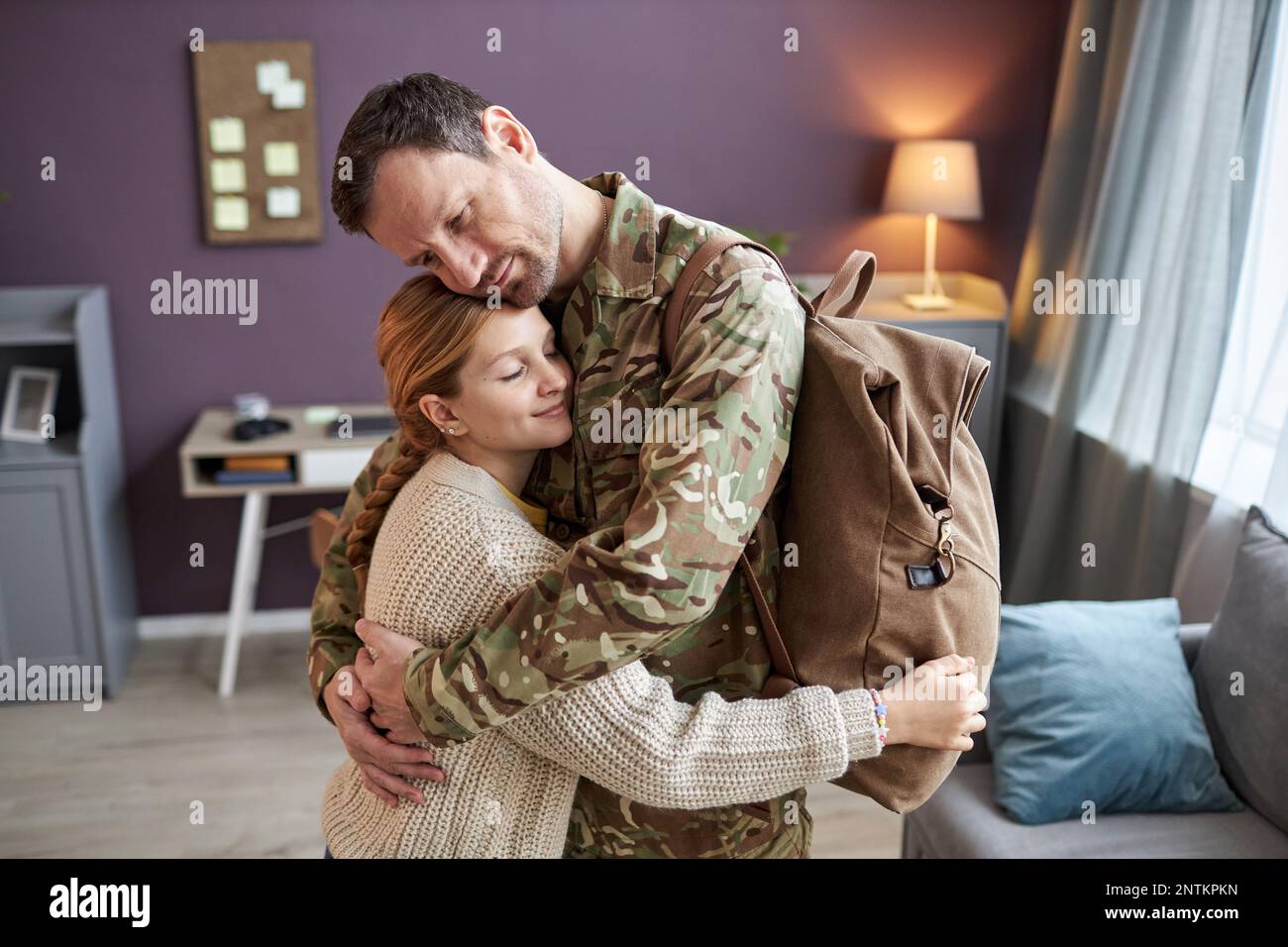 Waist up portrait of teen girl embracing military father coming back ...