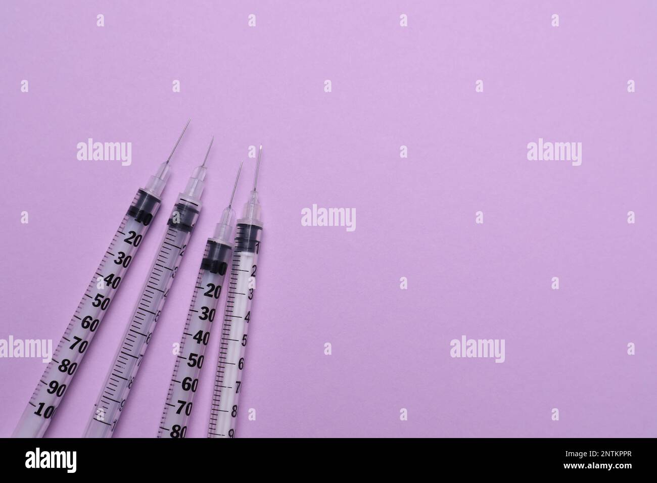 Disposable syringes with needles on violet background, flat lay. Space ...