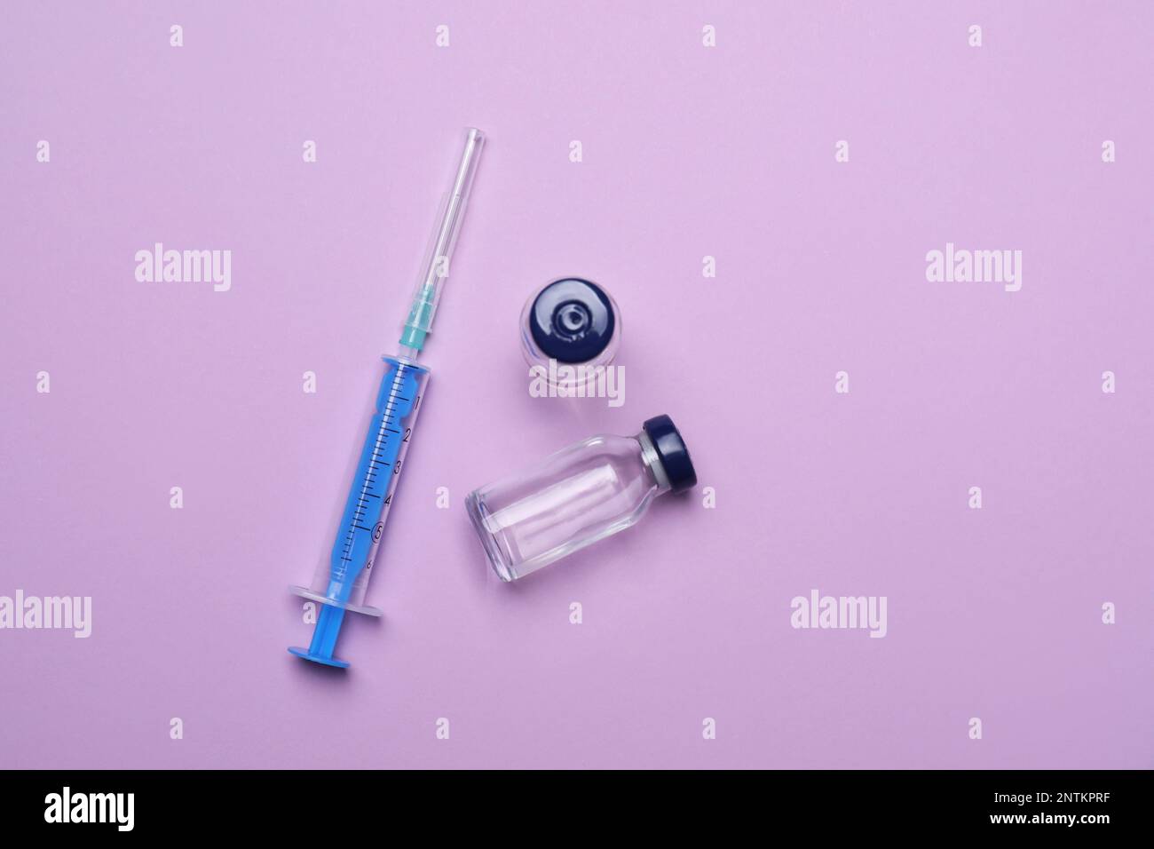 Disposable syringe and vials with medicine on violet background, flat ...
