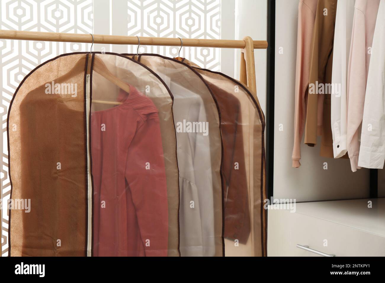 Garment bags with clothes on rack in dressing room Stock Photo - Alamy