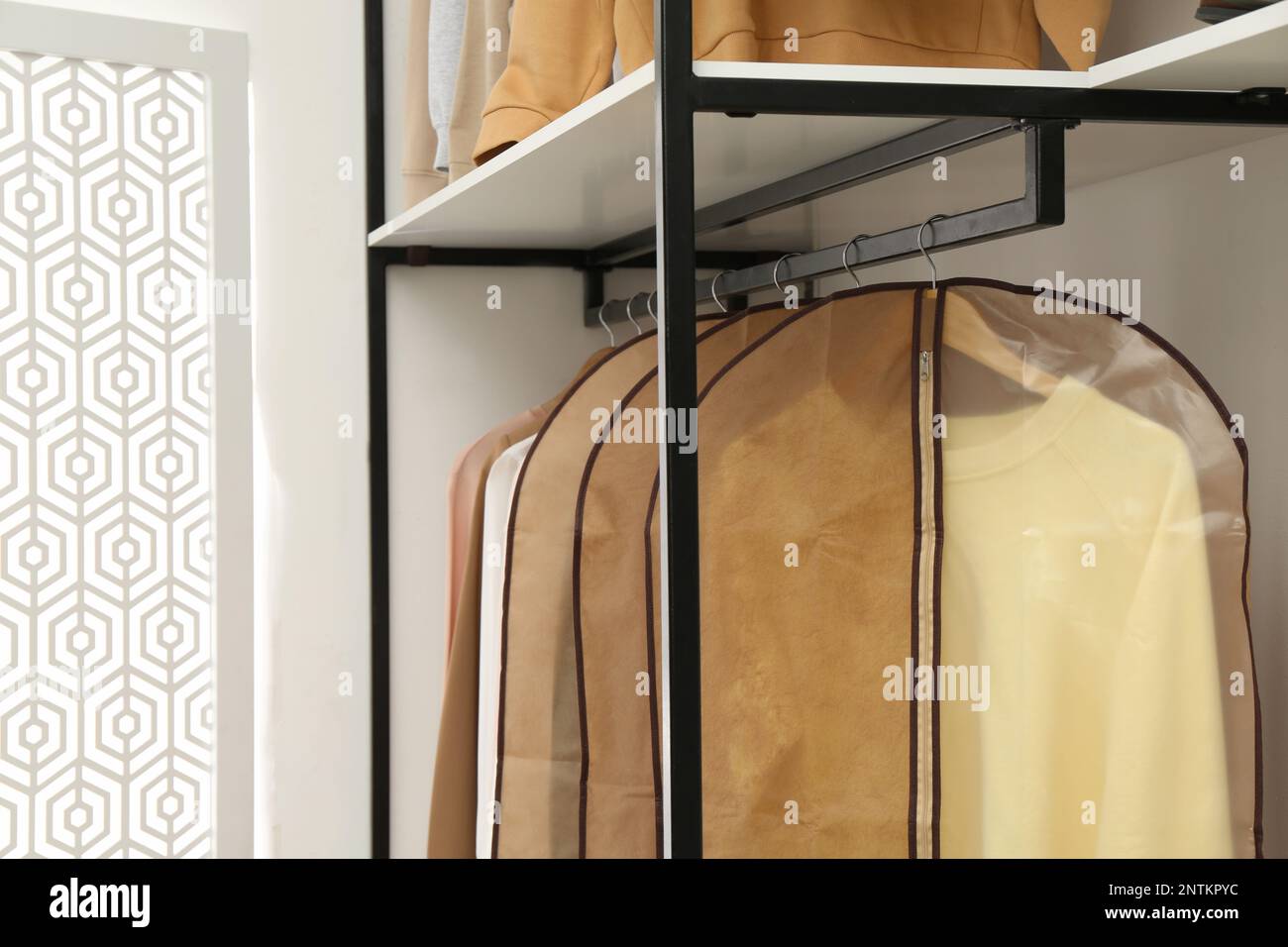 Garment bags with clothes on rack in dressing room. Space for text ...