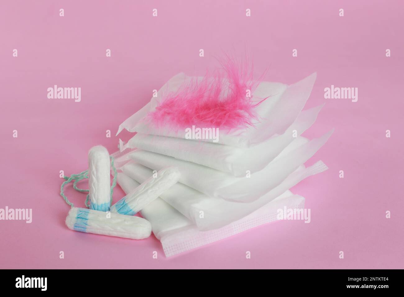 Menstrual pads with feather and tampons on pink background Stock Photo ...