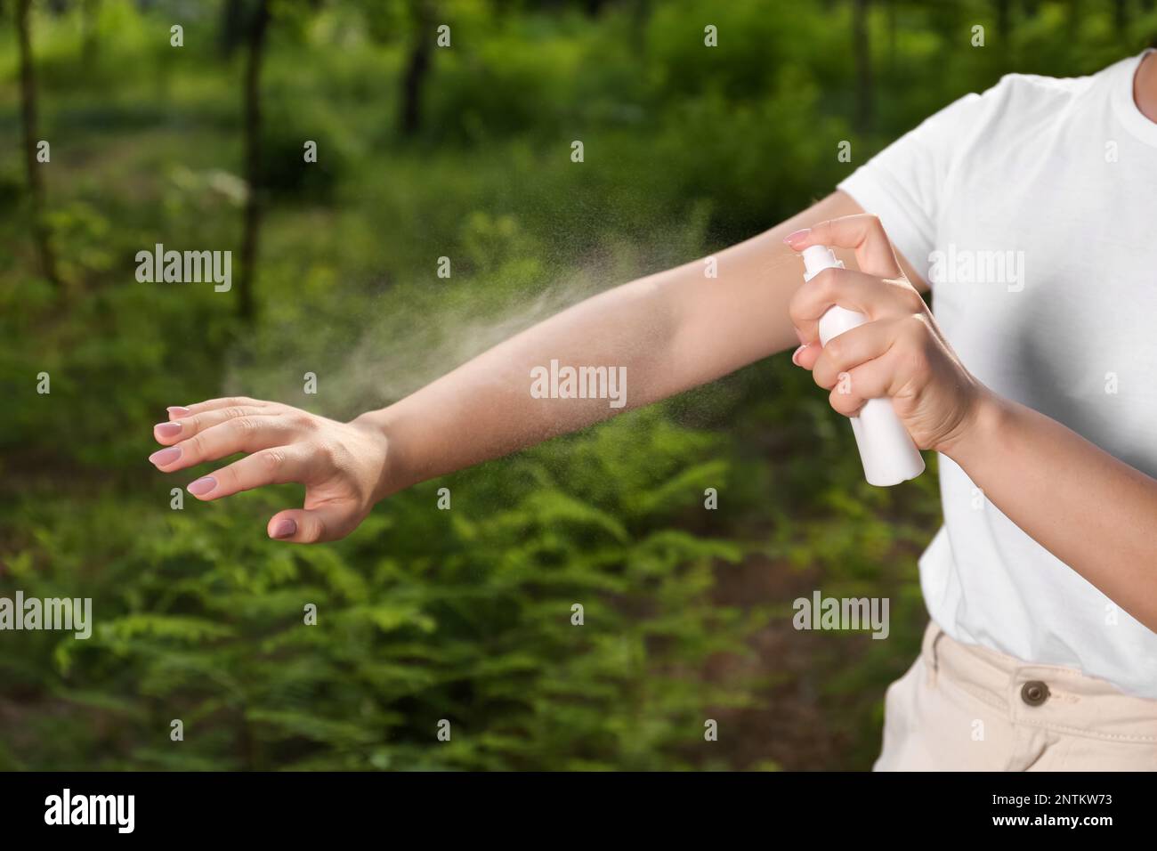 Woman applying insect repellent on arm in park, closeup. Tick bites ...