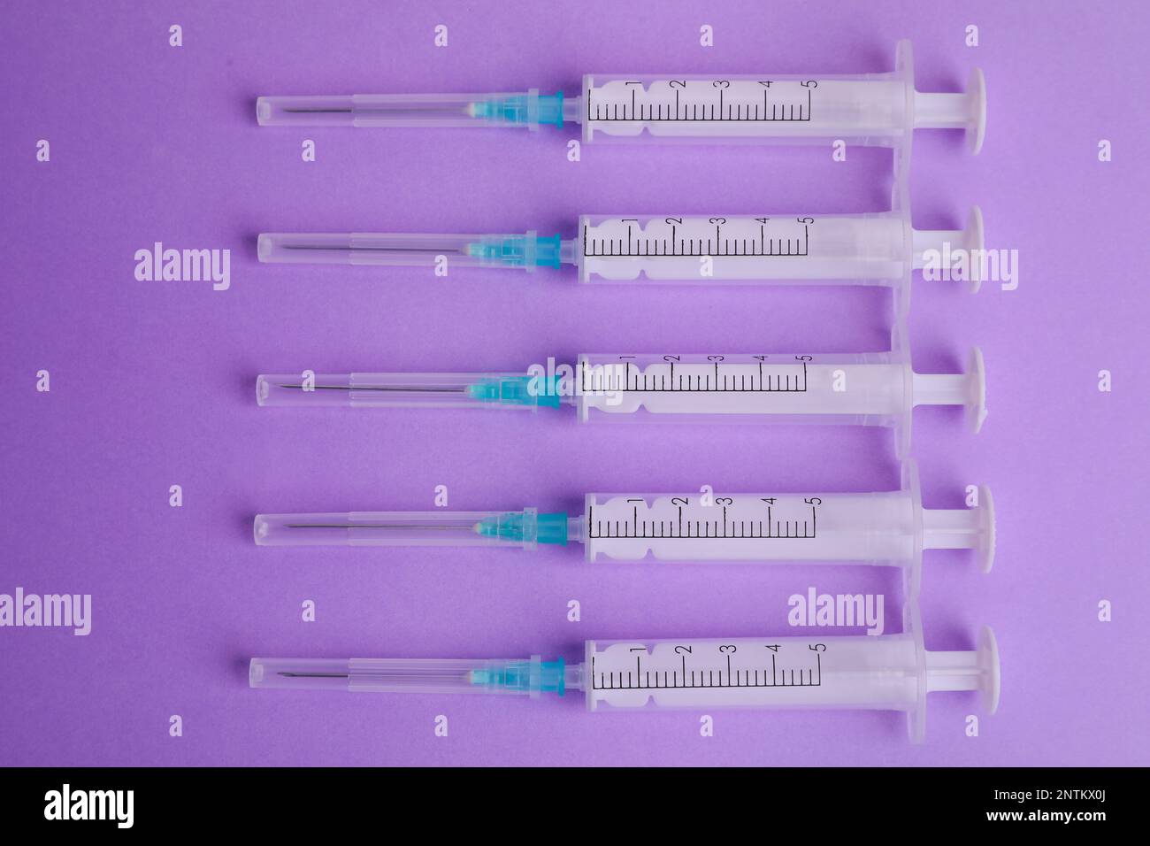 Disposable syringes with needles on violet background, flat lay Stock ...