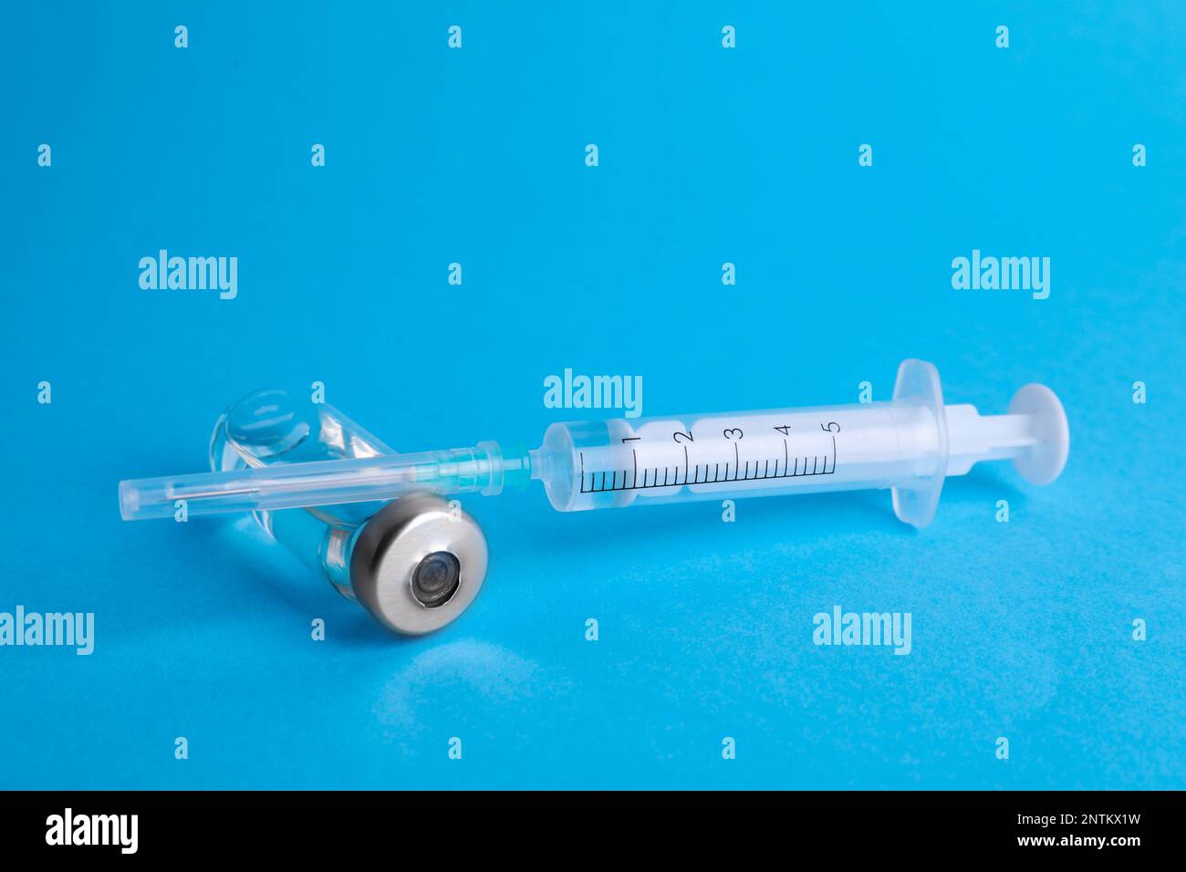 Disposable syringe with needle and vial on light blue background Stock ...