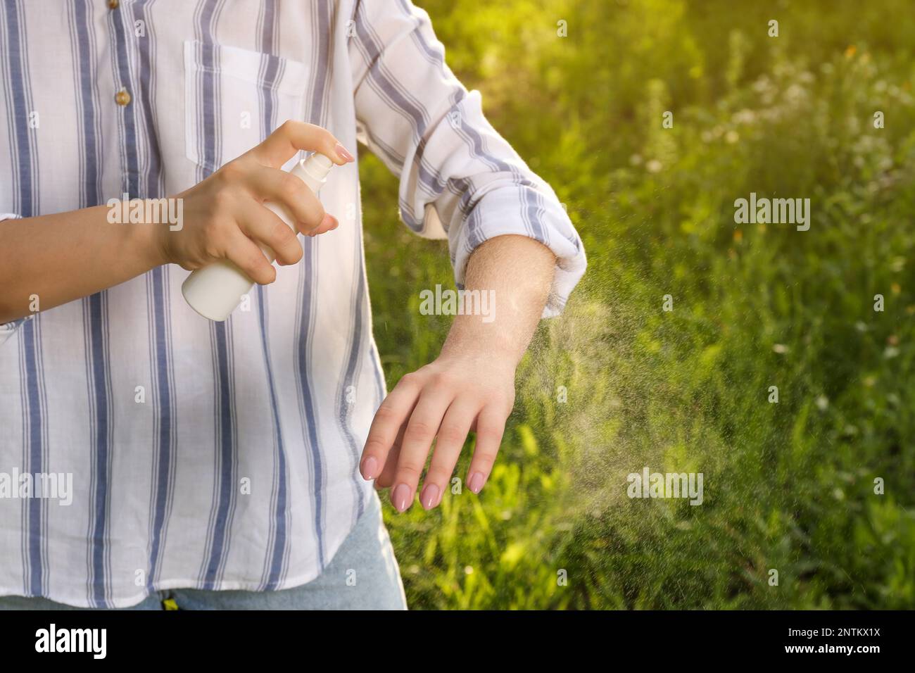 Woman applying insect repellent on arm in park, closeup. Tick bites ...