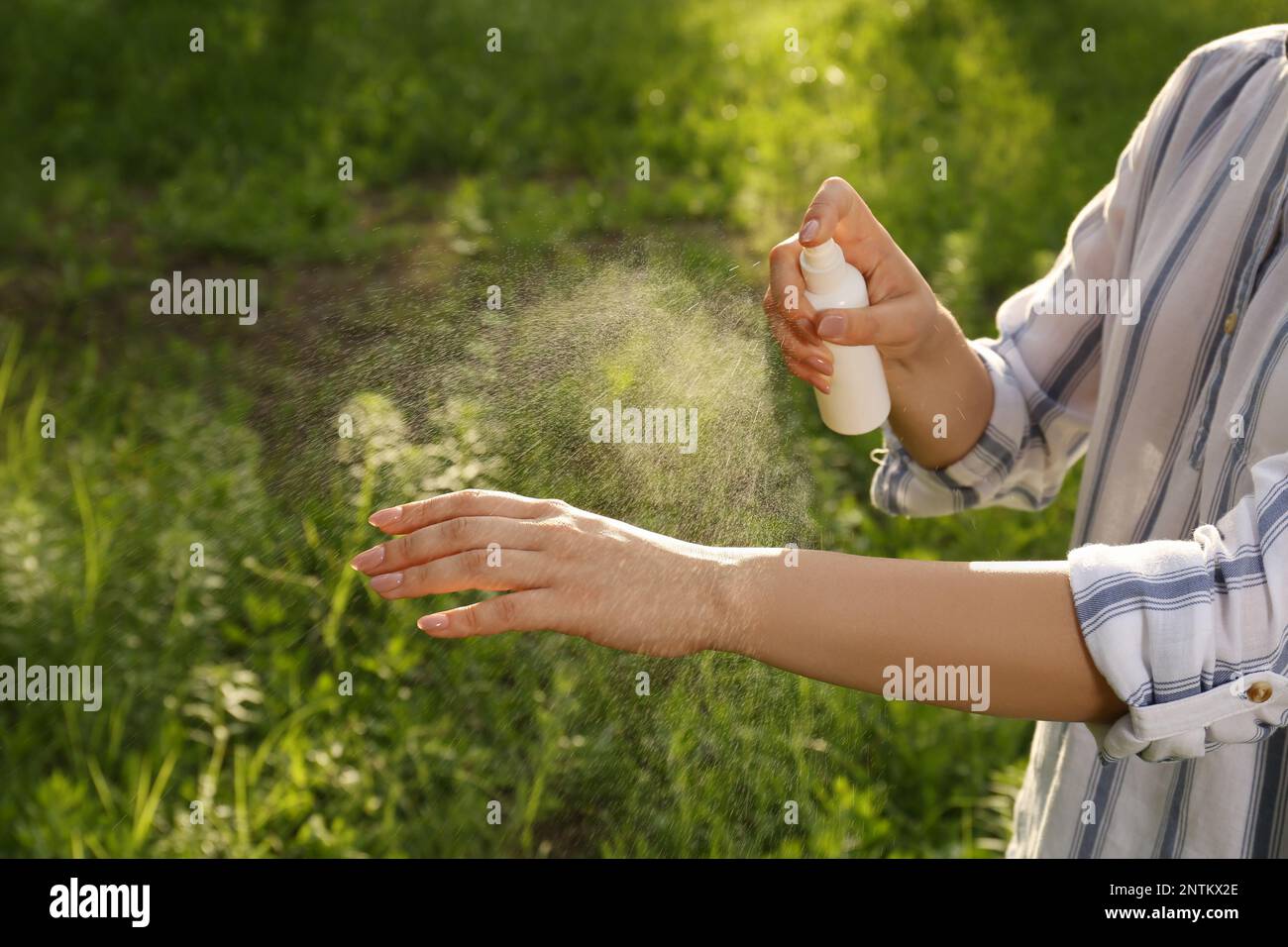 Woman applying insect repellent on hand in park, closeup. Tick bites ...