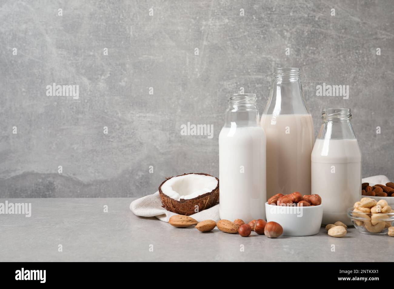 Different nut milks on light grey table. Space for text Stock Photo - Alamy