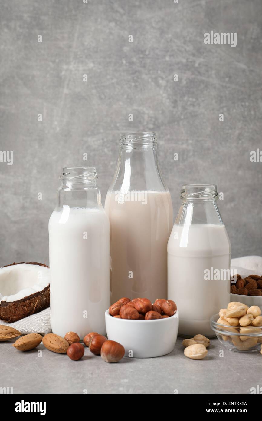 Different nut milks on light grey table Stock Photo - Alamy