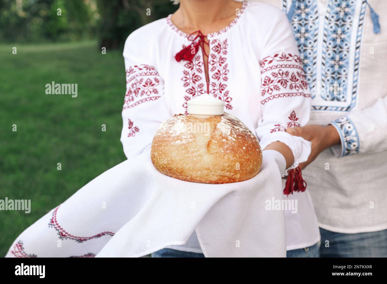 Mature couple in national clothes with bread and salt outdoors, closeup ...