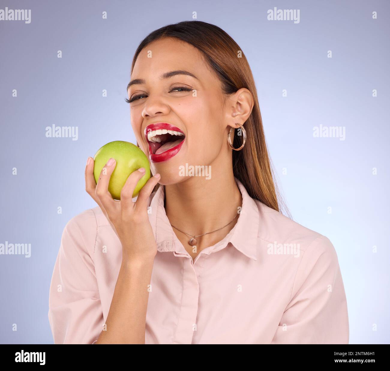 Portrait of woman eating apple isolated on studio background for ...