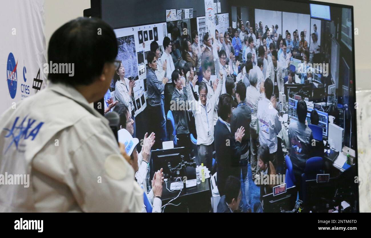 A monitor shows people at the JAXA control room celebrate as the ...