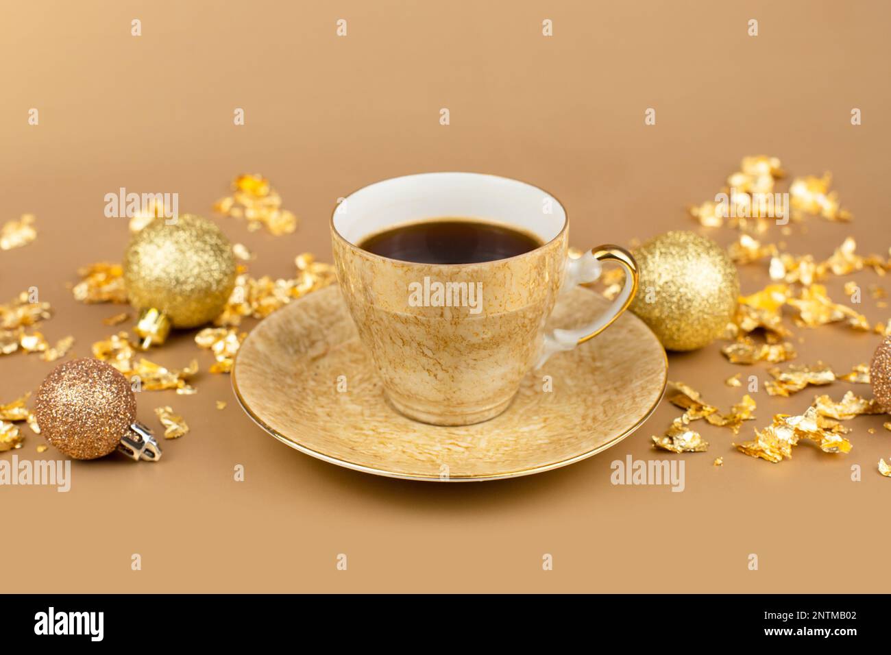Brown Cup of coffee with saucer, gold christmas balls and pieces of ...