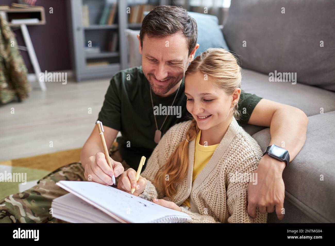 Portrait of caring military father helping daughter doing homework and ...