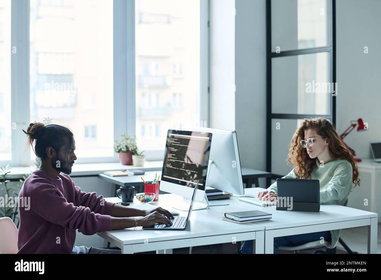 Young people working on computers with security codes in IT office ...