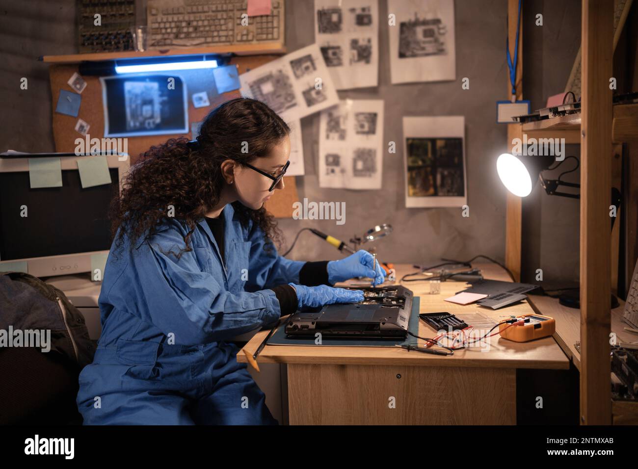 Female technician repairing broken laptop notebook computer with a ...