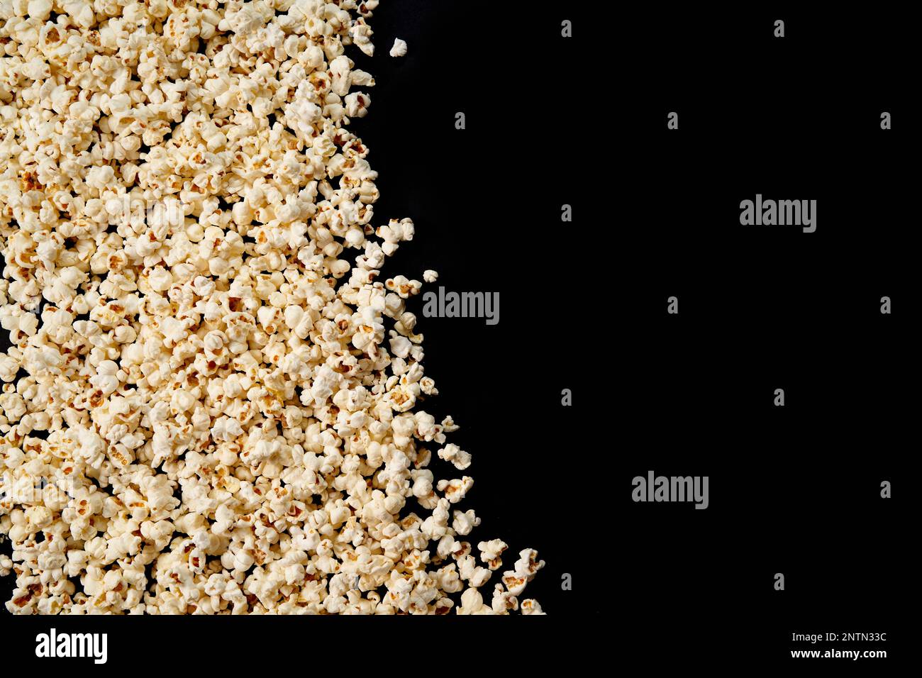 Scattered crispy popcorn on a black isolated background. View from ...