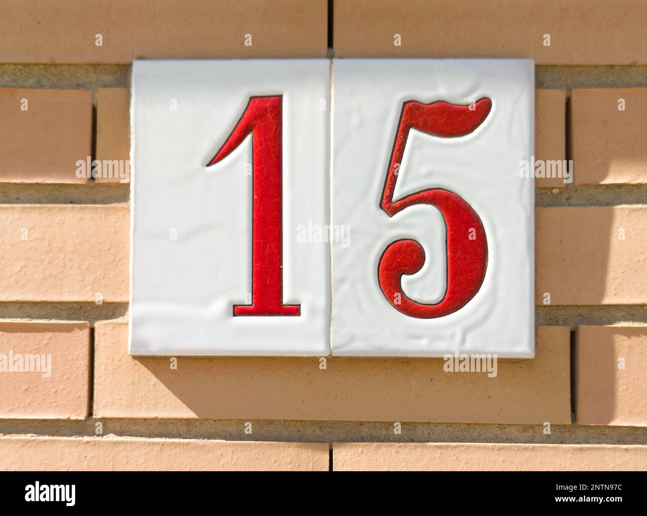 House number 15 over brick sunny wall. Houses with personality concept ...