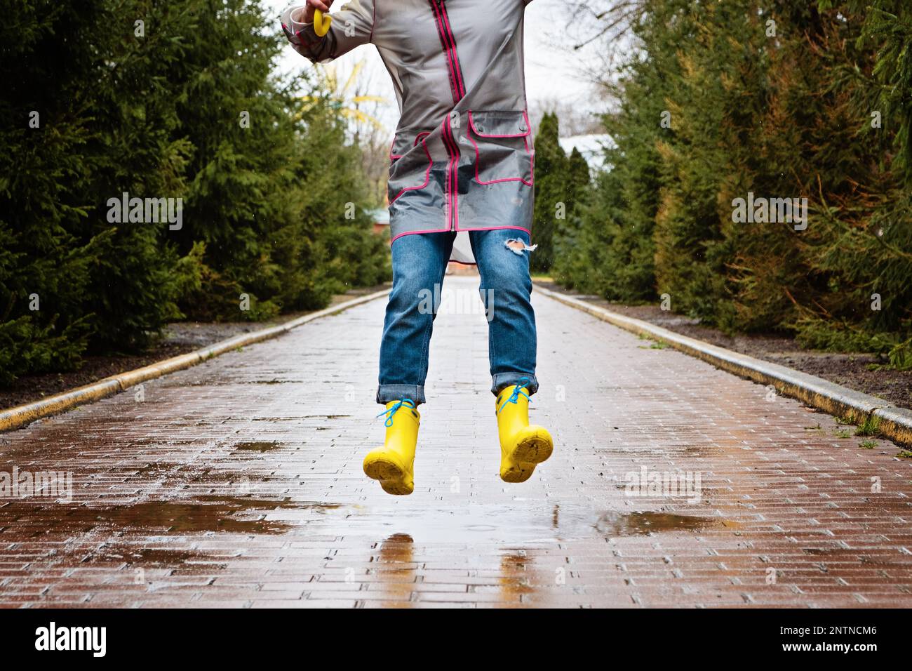 Jumping in puddle. Female legs in yellow rubber boots jumping on the ...