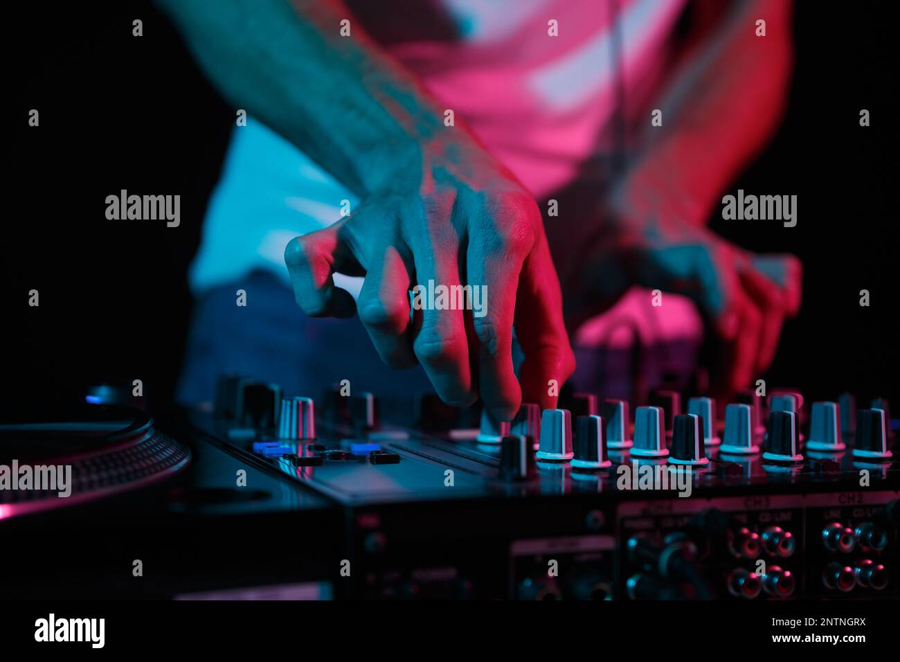 Disc jockey mixing techno music on rave party. Disk jokey adjusting ...