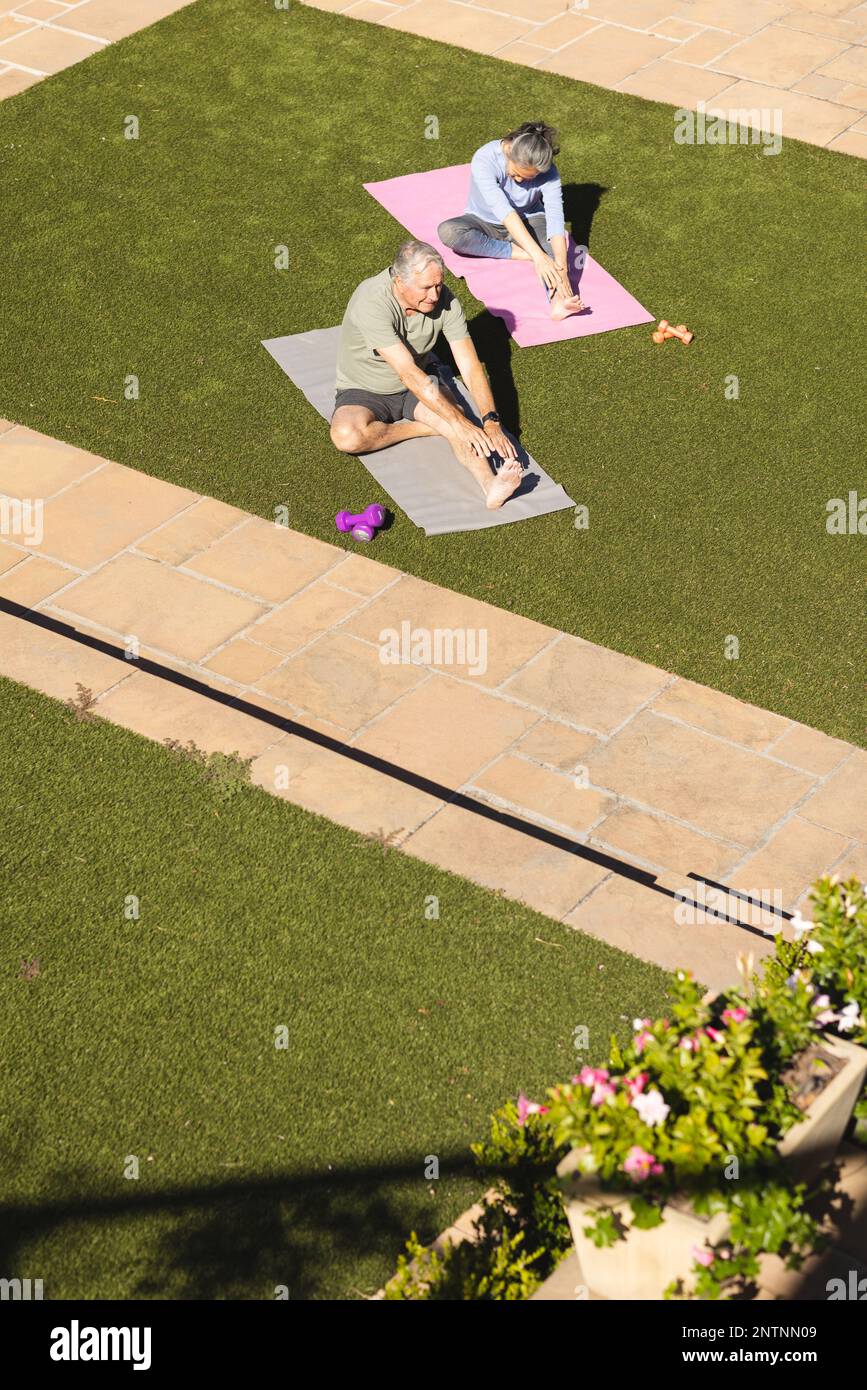 Happy senior diverse couple doing yoga and stretching in garden Stock ...