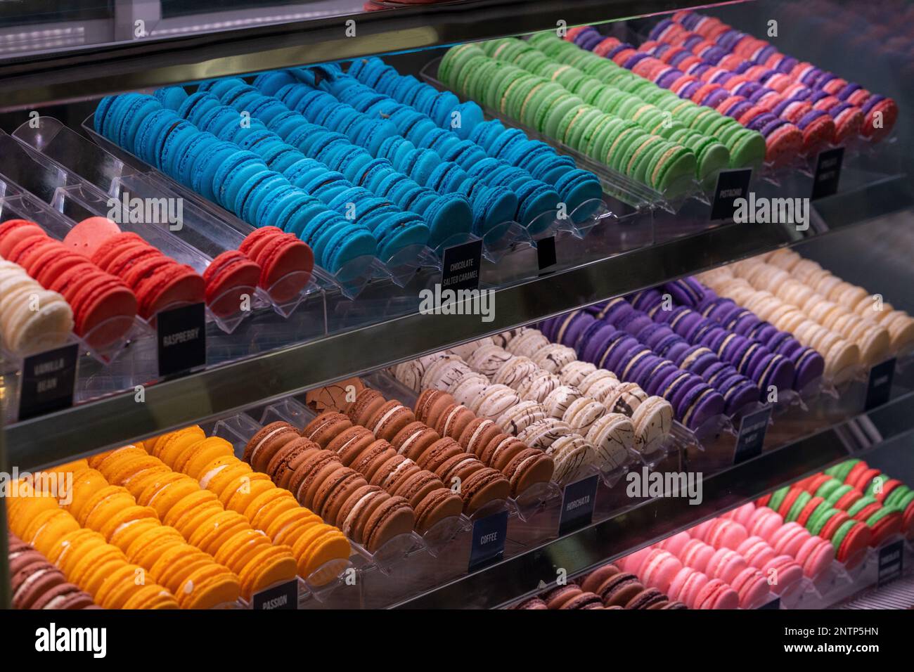 An assortment of vibrant French macarons on display in a bakery window ...