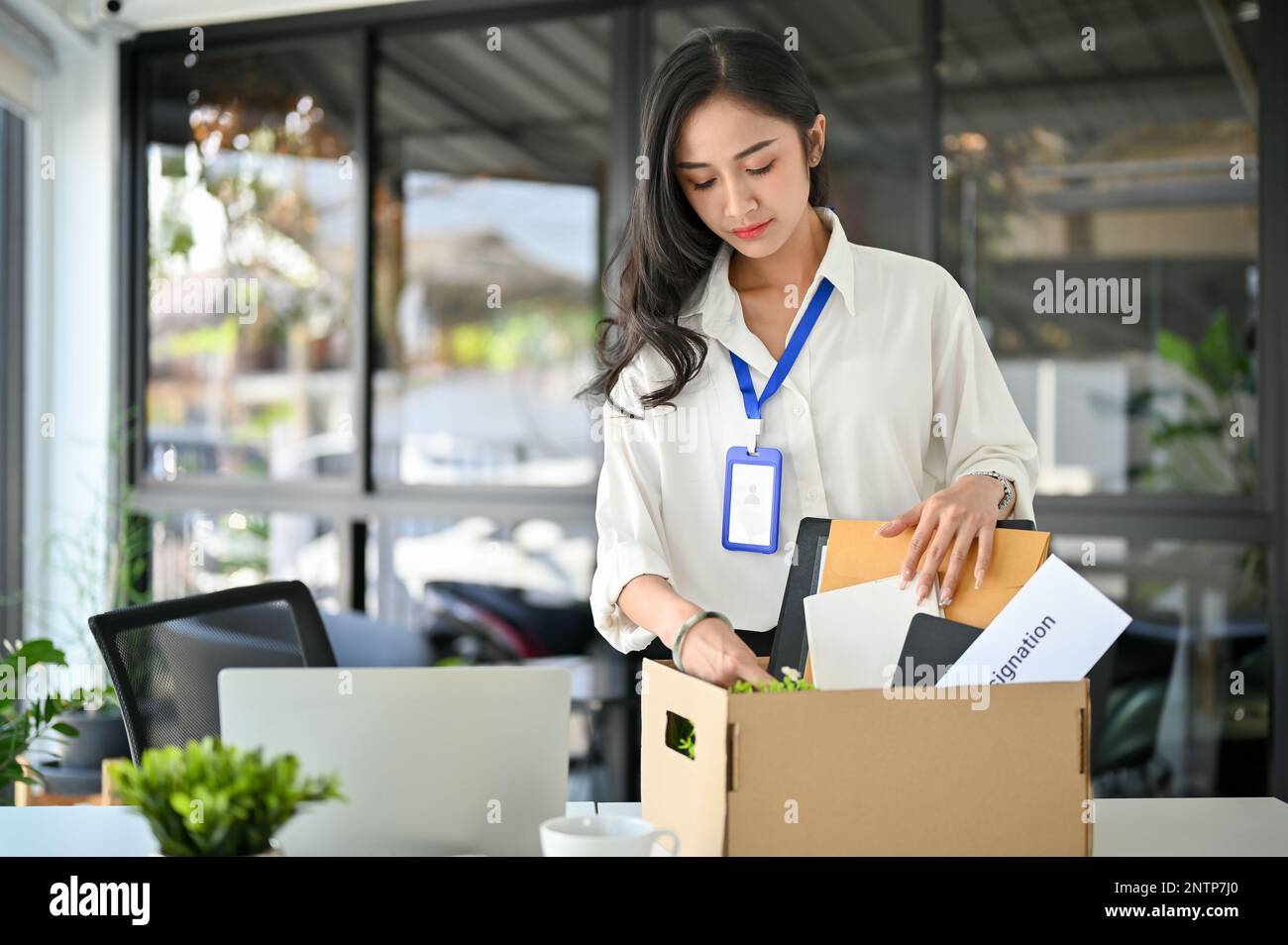 Sad and unhappy millennial Asian female office worker packing her stuff ...