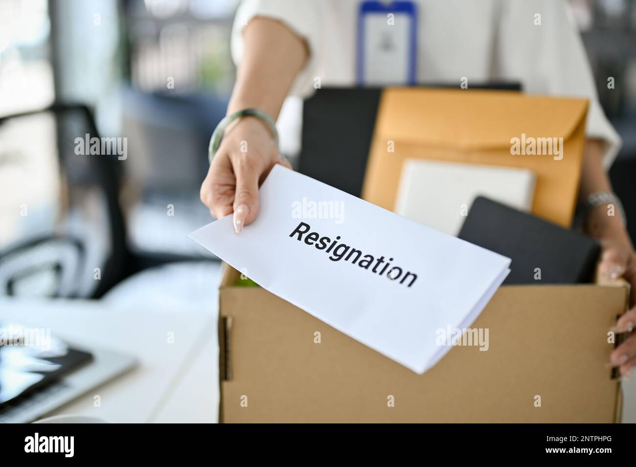 Close-up image of a female office worker handing a resignation letter ...