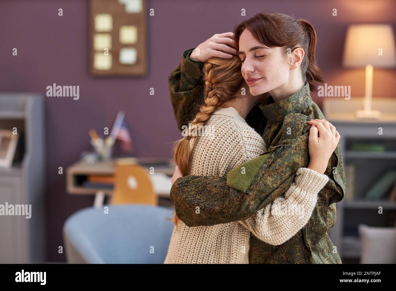 Side view portrait of young military mom embracing daughter with eyes ...