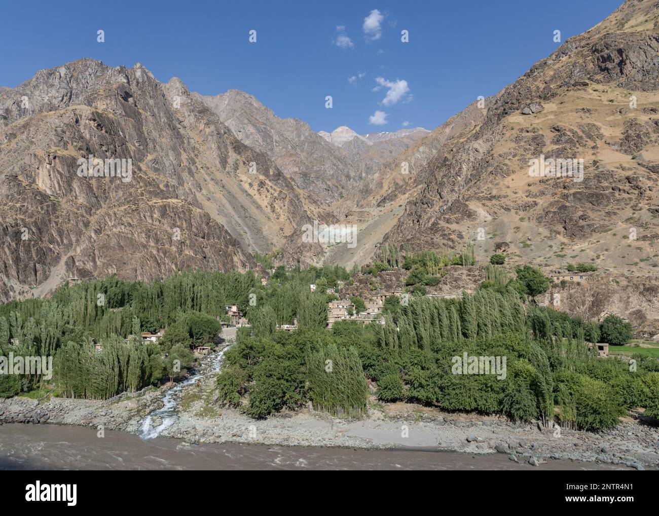 Landscape view of mountain village amidst trees and torrent on Afghan ...