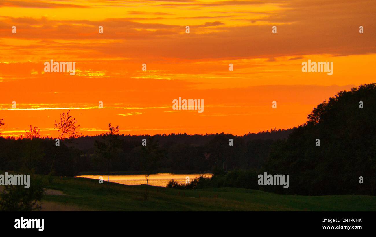 powerful sunset in red, yellow and golden light. Meadow in the ...