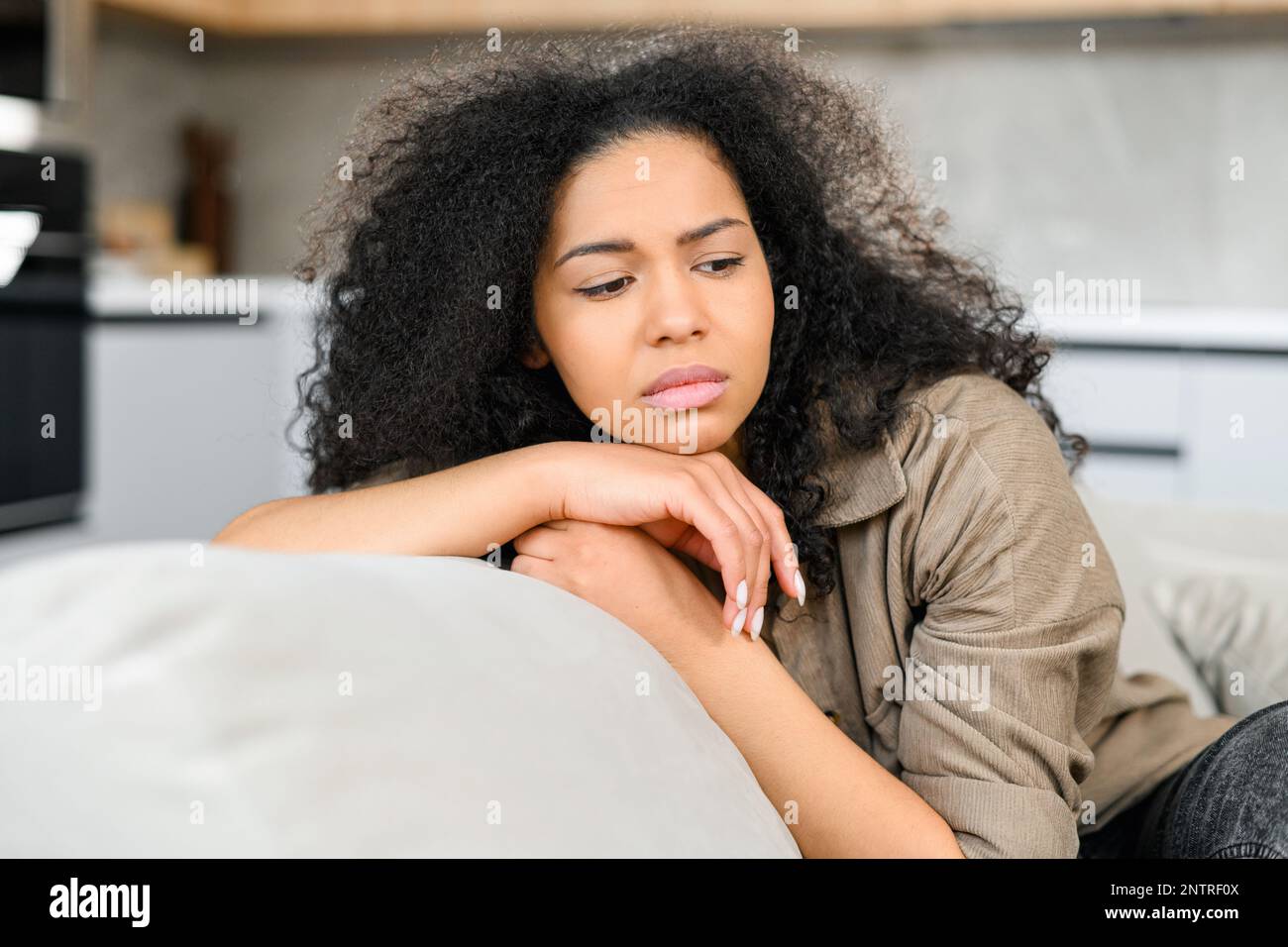 Multiracial woman feels panic attack, sits on the sofa at home, looks ...