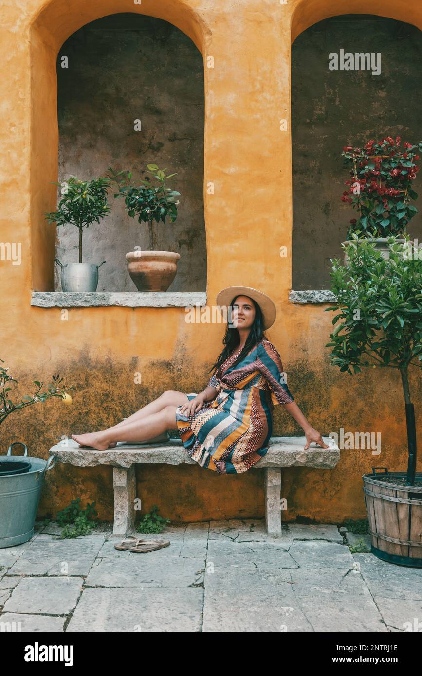 Beautiful Happy Girl Wearing Colorful Dress And Sun Hat Sitting On