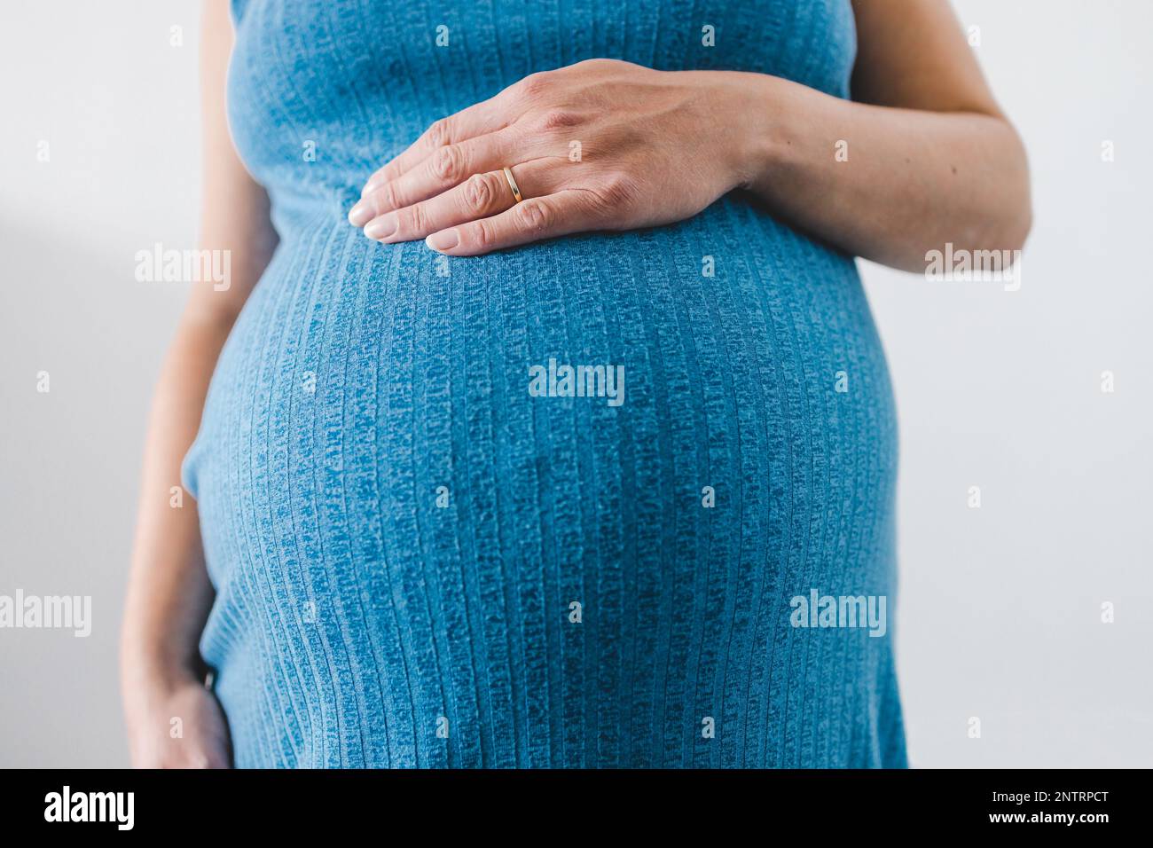 pregnant woman cudling her bump in the ninth month, mid-section showing ...
