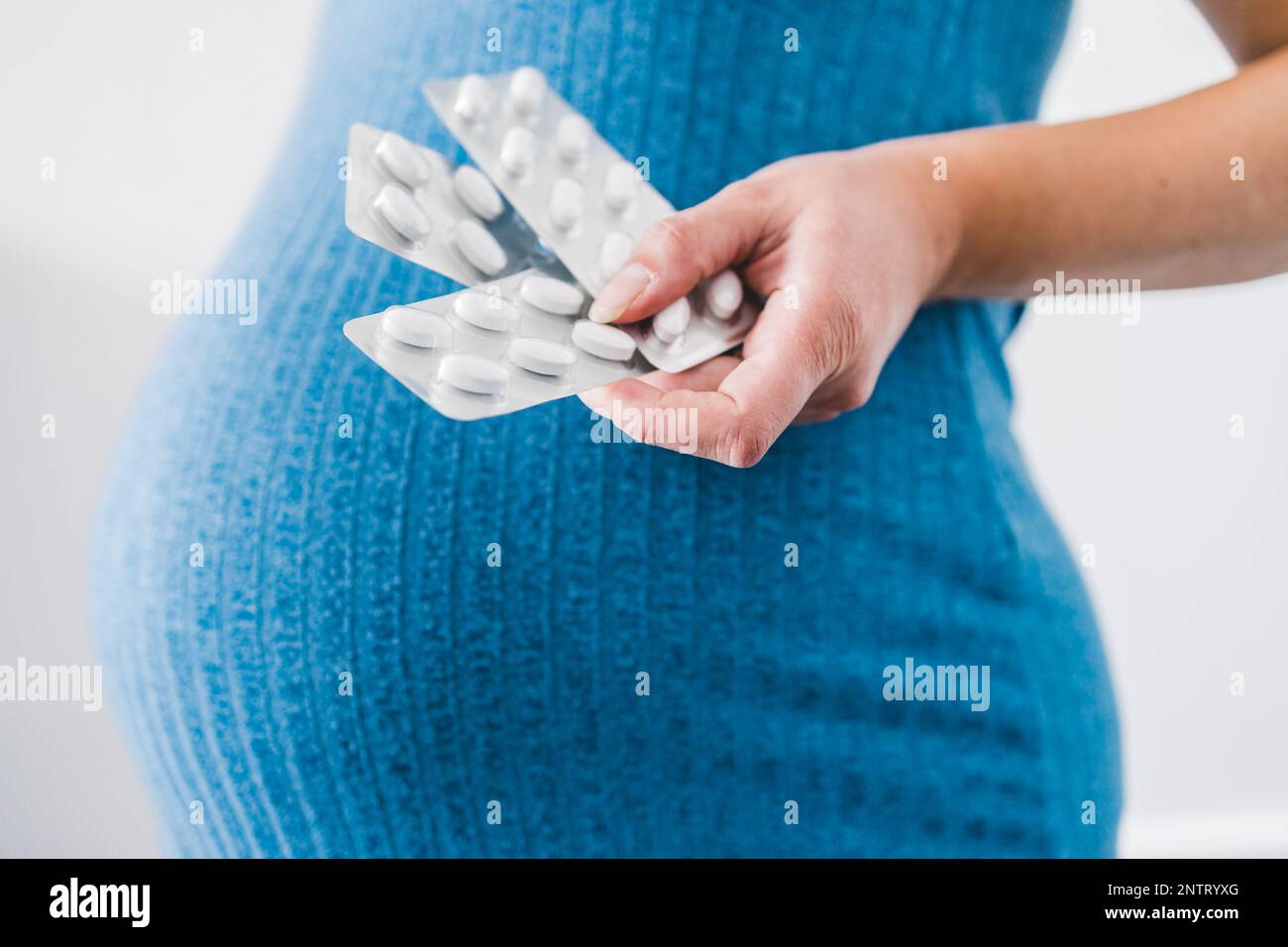 pregnant woman holding multivitamins tablets in her hand and showing ...