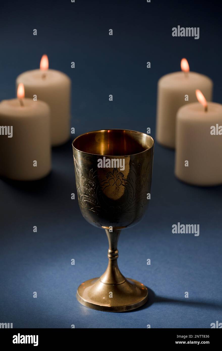 Golden Christian chalice with 4 candles with flames, blue altar, brown ...