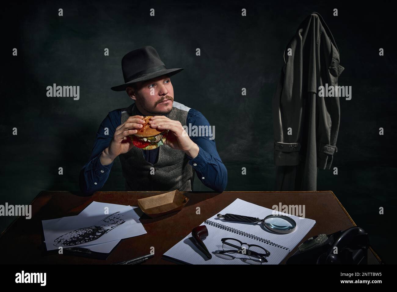 Professional detective in fedora hat sitting at table and eating ...
