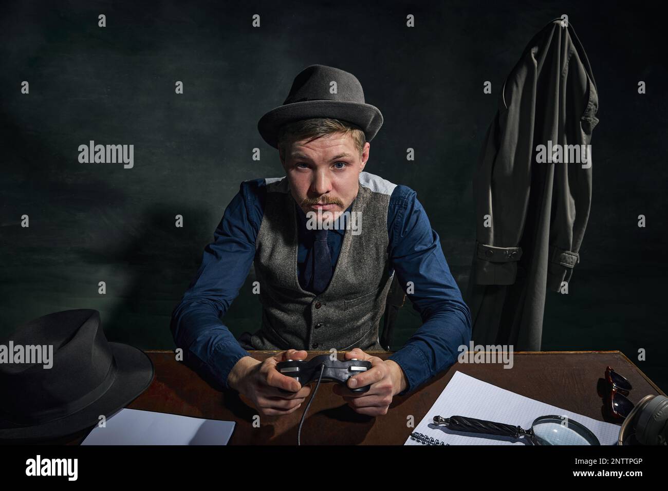 Professional detective in fedora hat sitting at table and playing ...