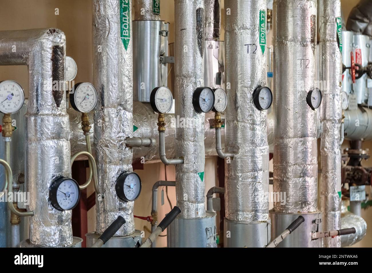 Plumbing pipes in the basement with pressure gauges on them. Russian ...